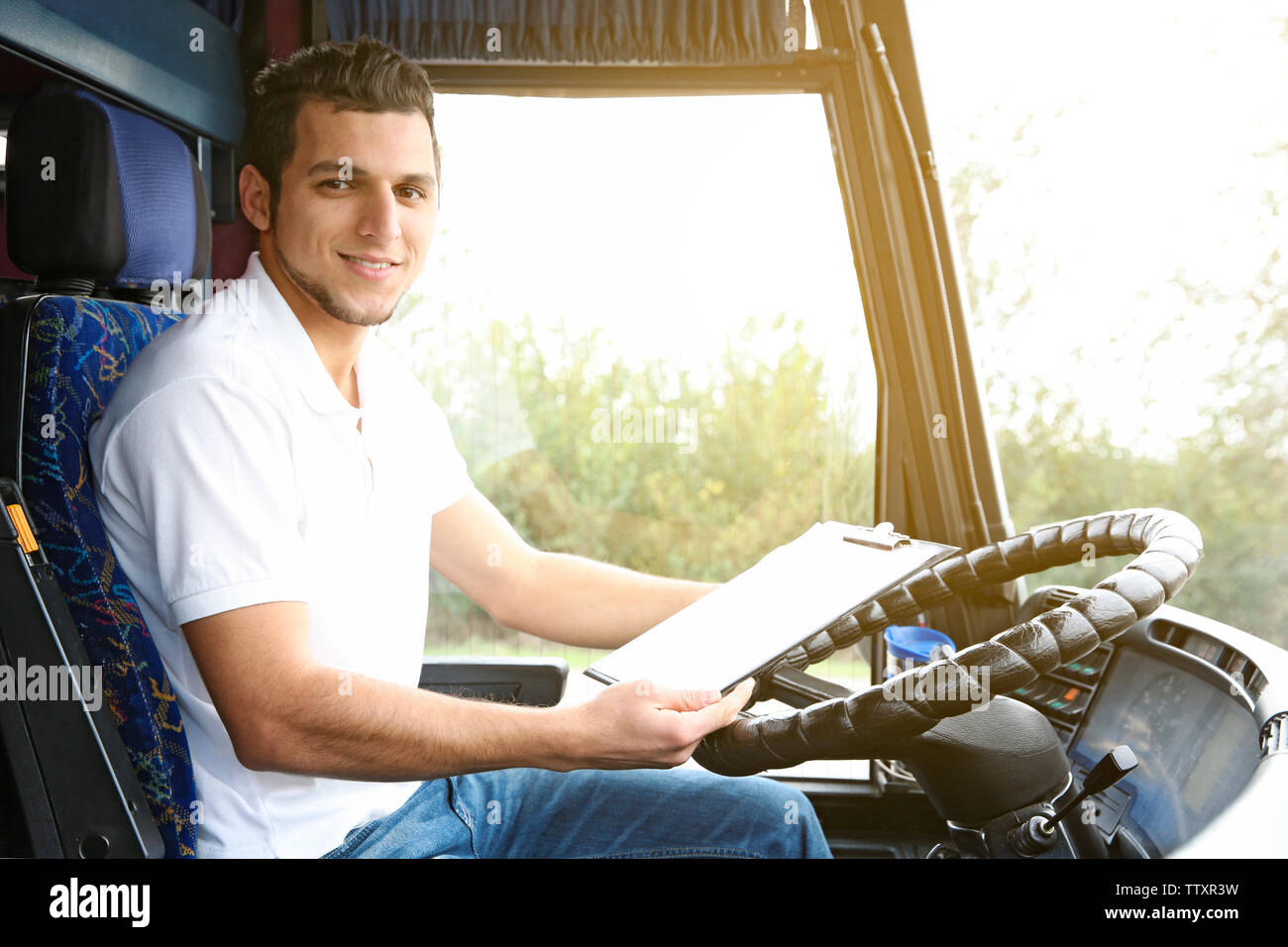 Handsome driver with clipboard sitting in bus Stock Photo - Alamy