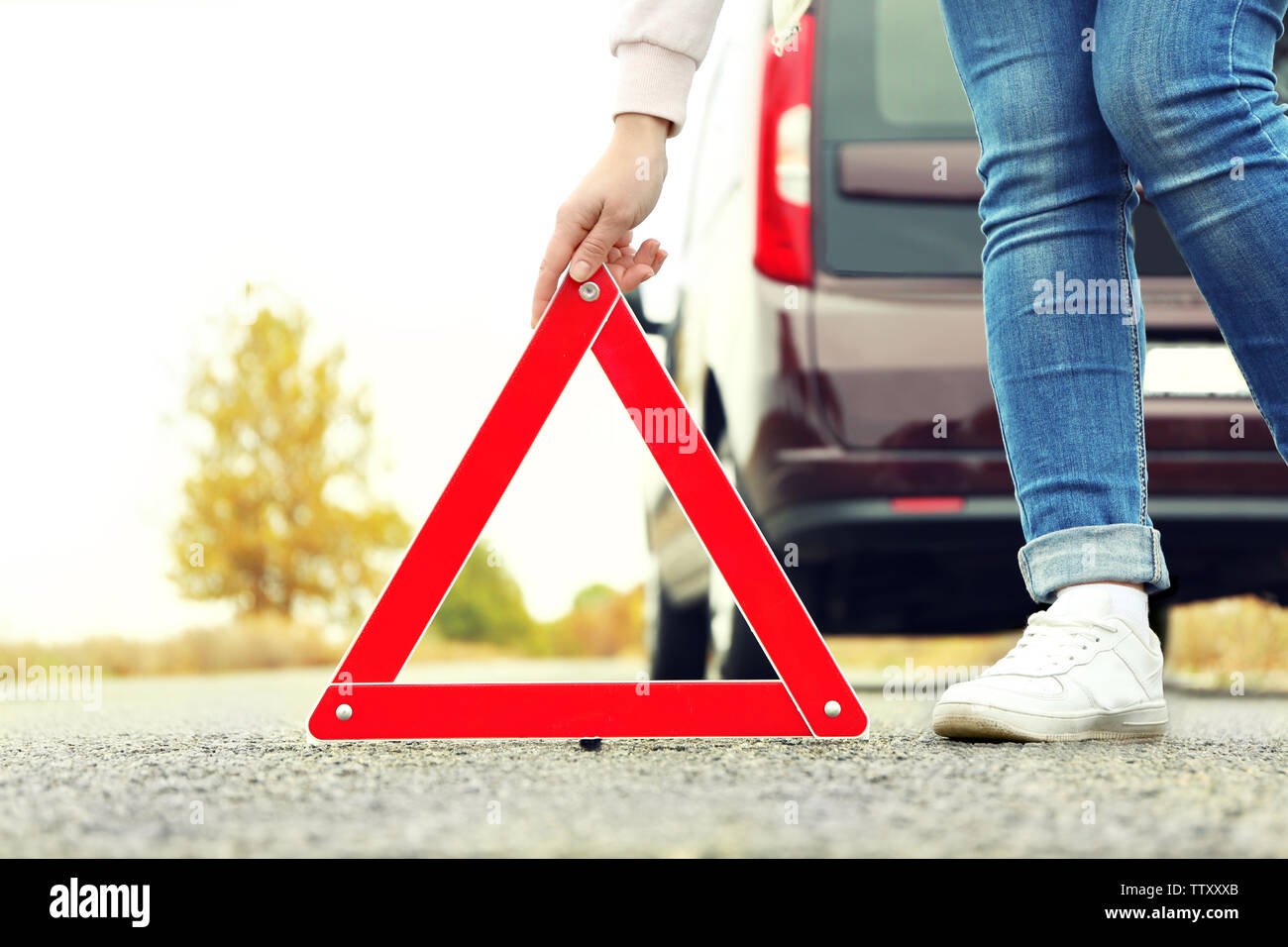 Female driver putting out traffic warning sign on road Stock Photo - Alamy