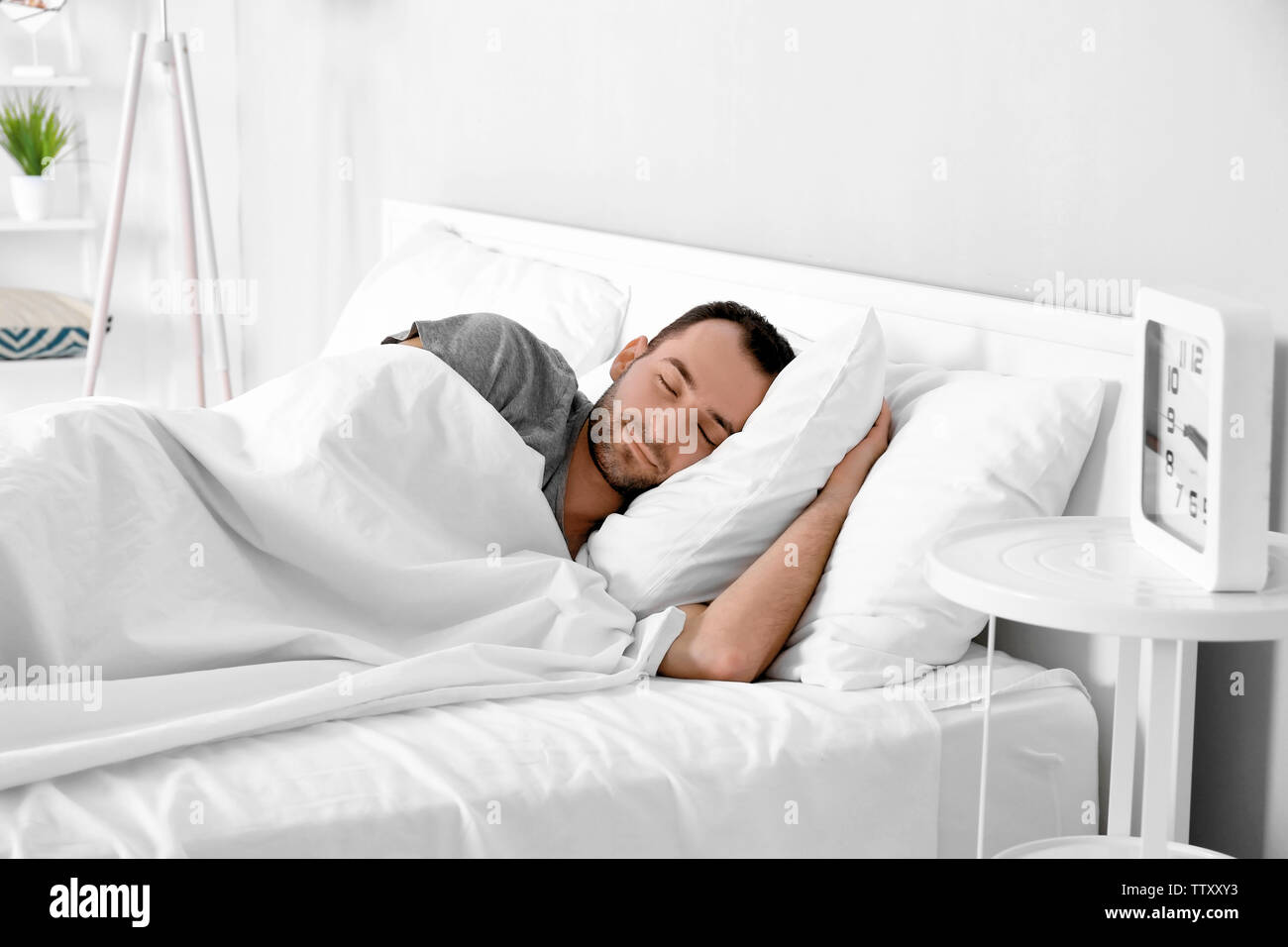 Tired young man sleeping in bed Stock Photo - Alamy