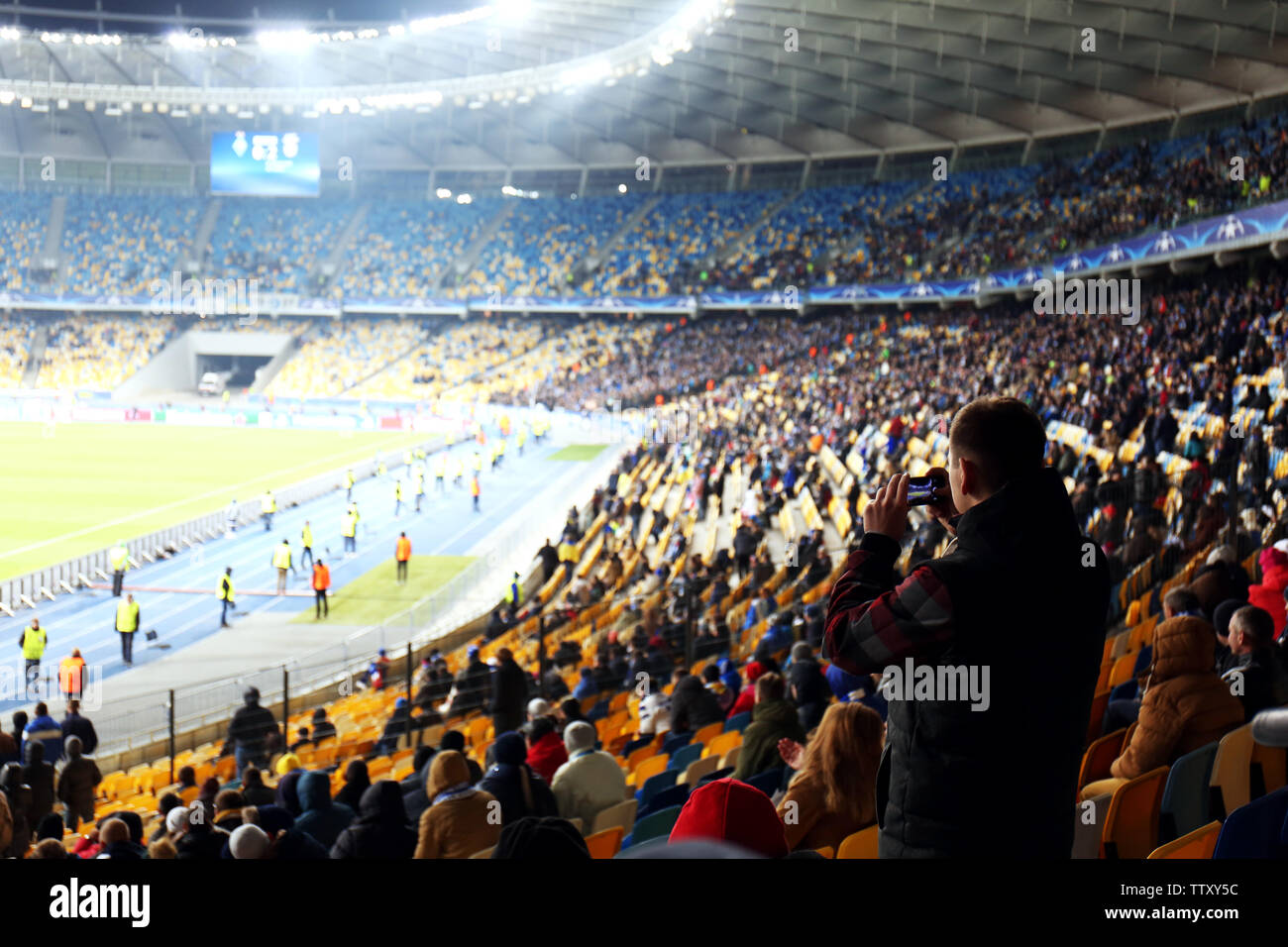 Fans watching football game at stadium Stock Photo - Alamy