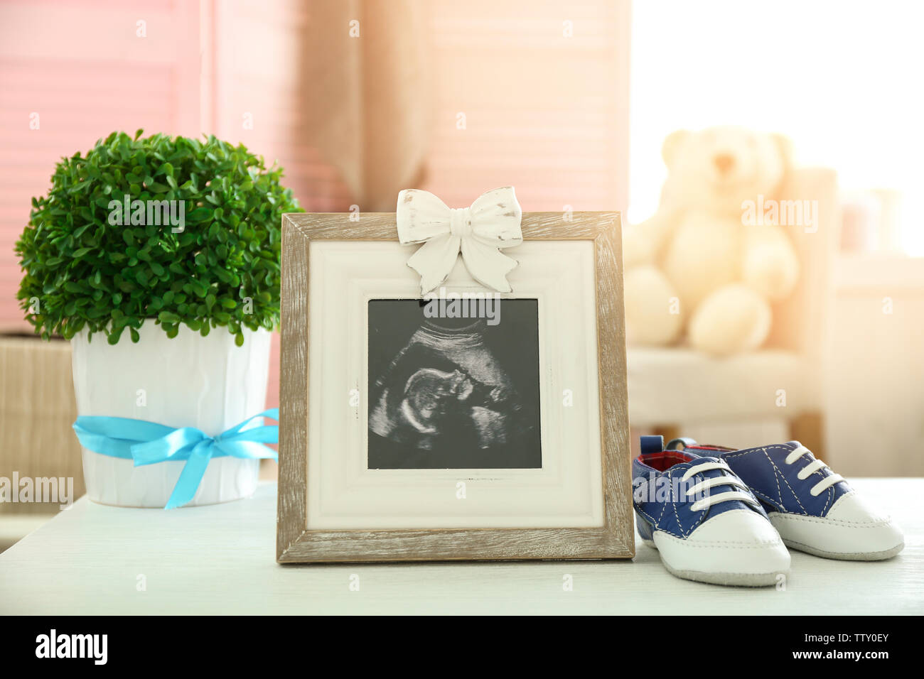 Frame with ultrasound photo and baby shoes on table Stock Photo - Alamy