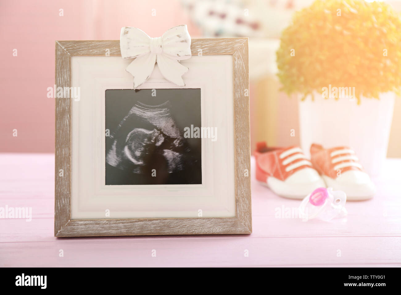Frame with ultrasound photo and baby shoes on table Stock Photo - Alamy
