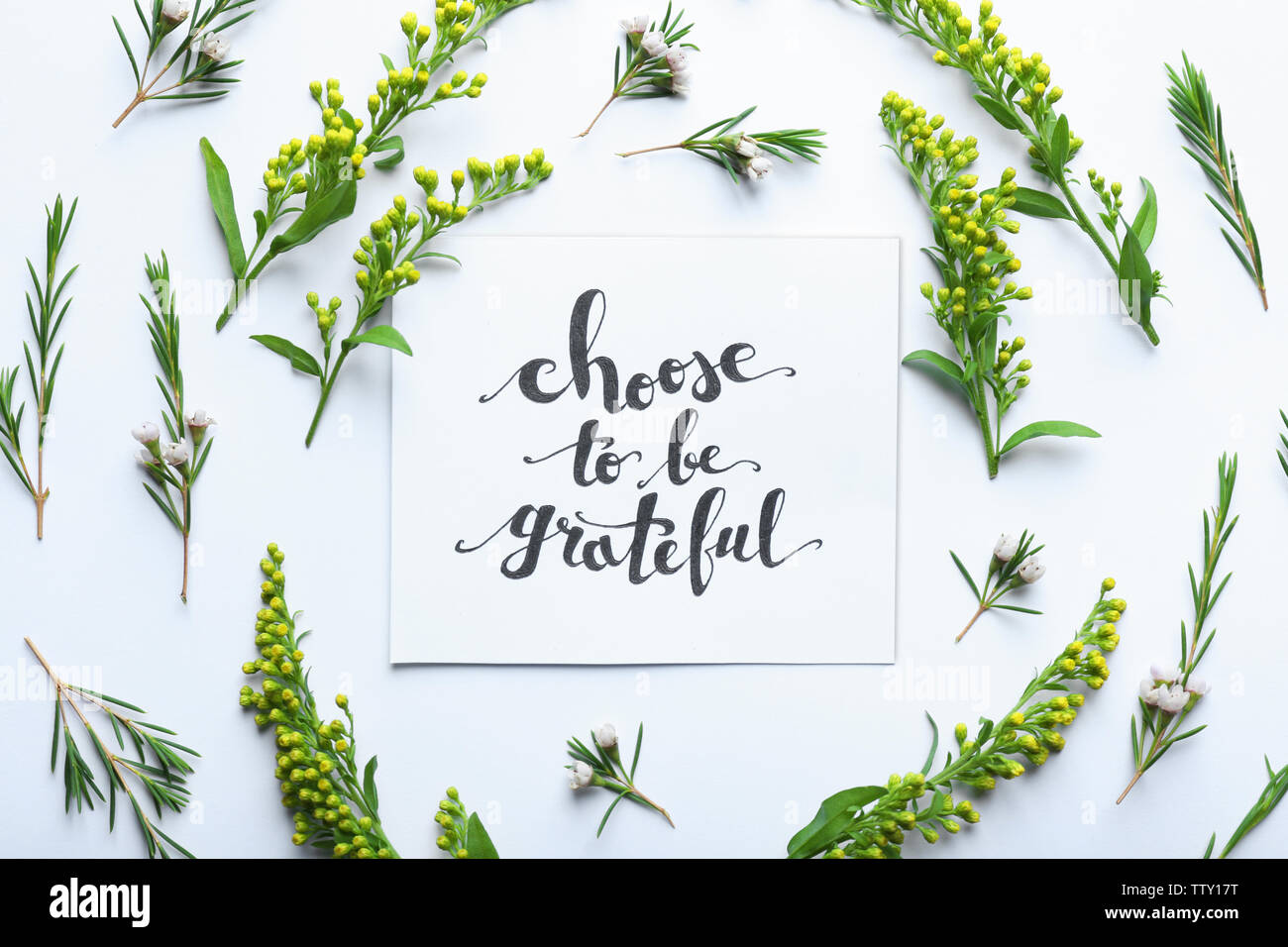 Inscription "CHOOSE TO BE GRATEFUL" written on paper with flowers on ...