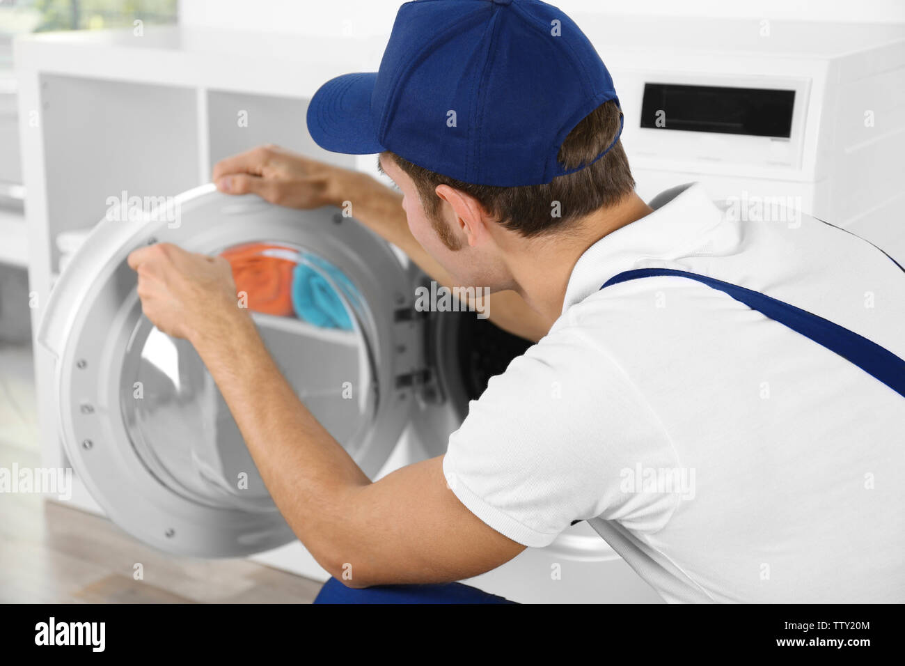 Plumber repairing washing machine Stock Photo - Alamy