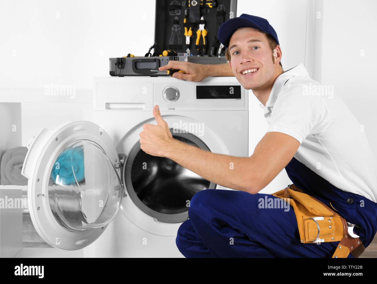 Plumber repairing washing machine Stock Photo - Alamy