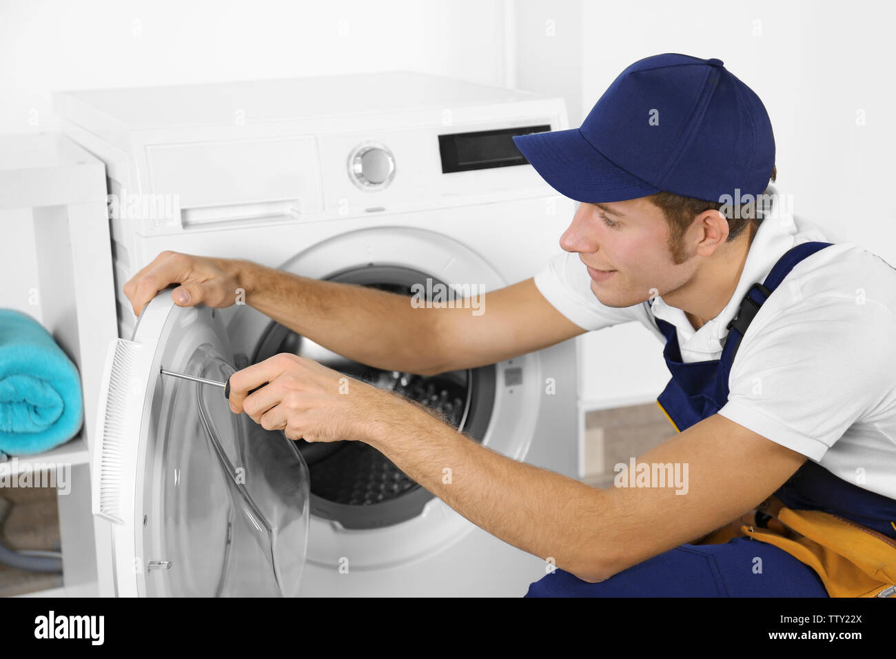 Plumber repairing washing machine Stock Photo - Alamy