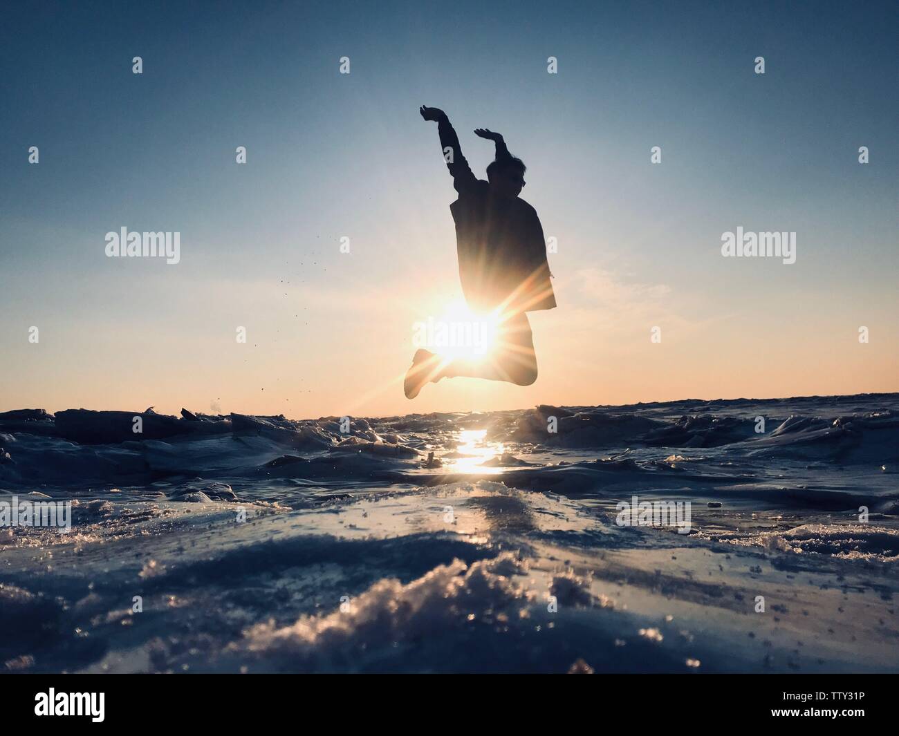 In the face of the sun, jumping up, backlit portraits, frozen sea Stock ...