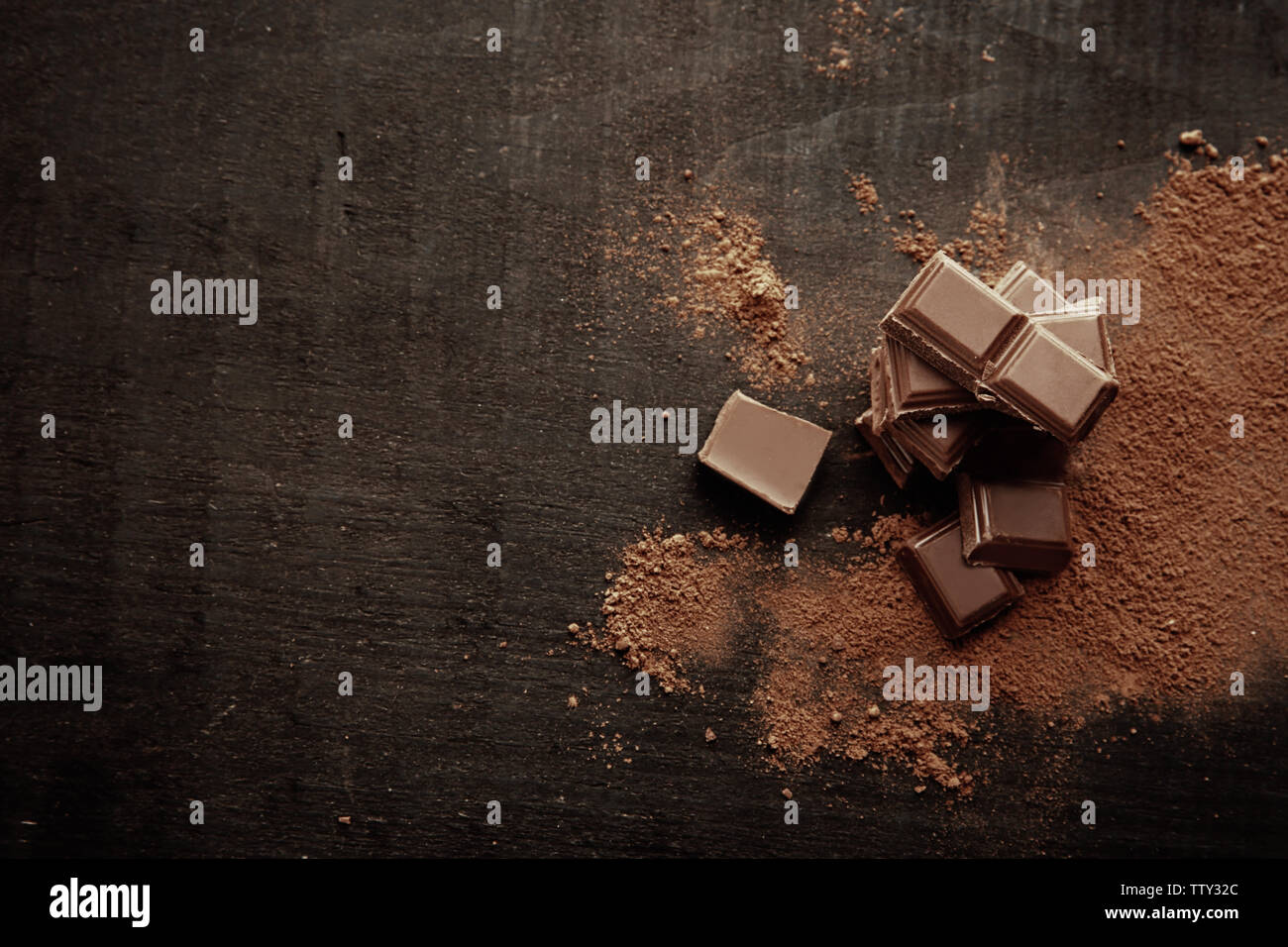 Broken chocolate pieces and cocoa powder on wooden background Stock ...