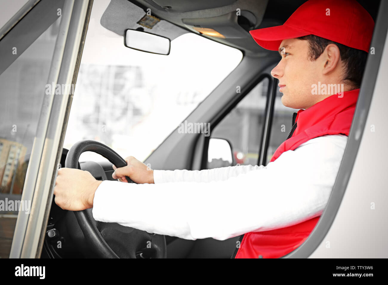 Young male courier driving delivery service van Stock Photo - Alamy