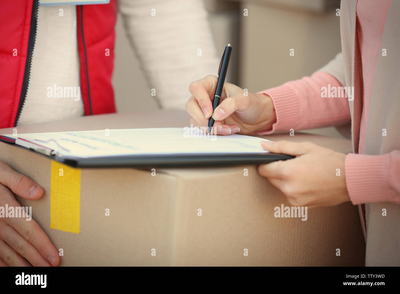 Young woman signing receipt for delivering parcel from male courier ...