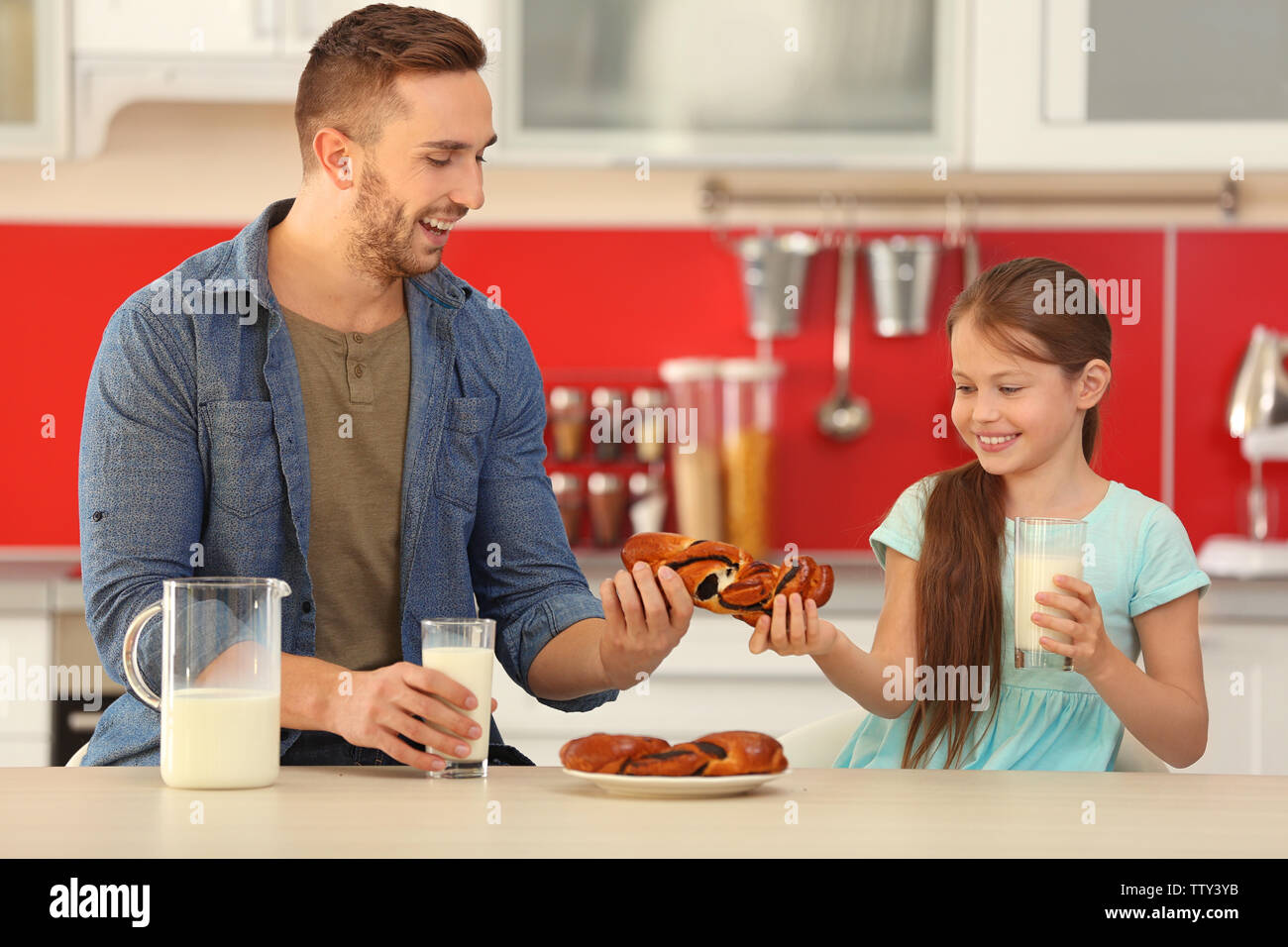 Father and daughter sharing bun at kitchen Stock Photo - Alamy