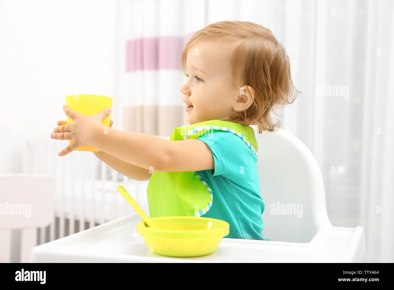 Cute little girl in high chair at baby room Stock Photo - Alamy
