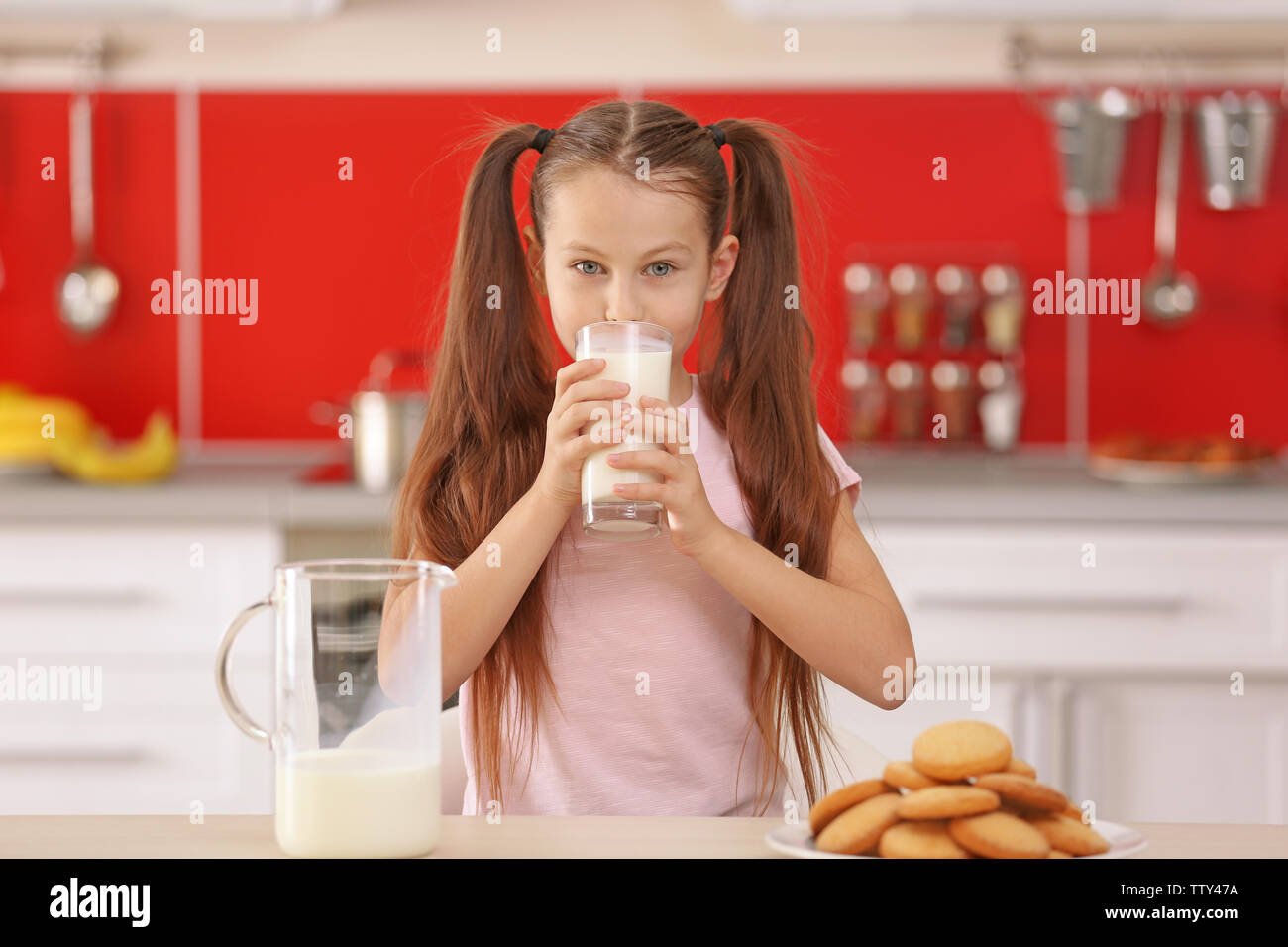 Cute little girl drinking fresh milk at kitchen Stock Photo - Alamy