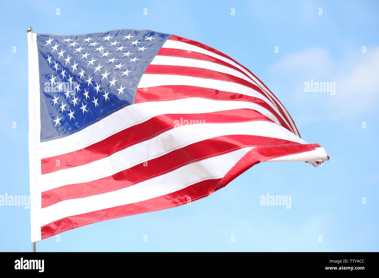 Ruffled American flag on blue sky background Stock Photo - Alamy