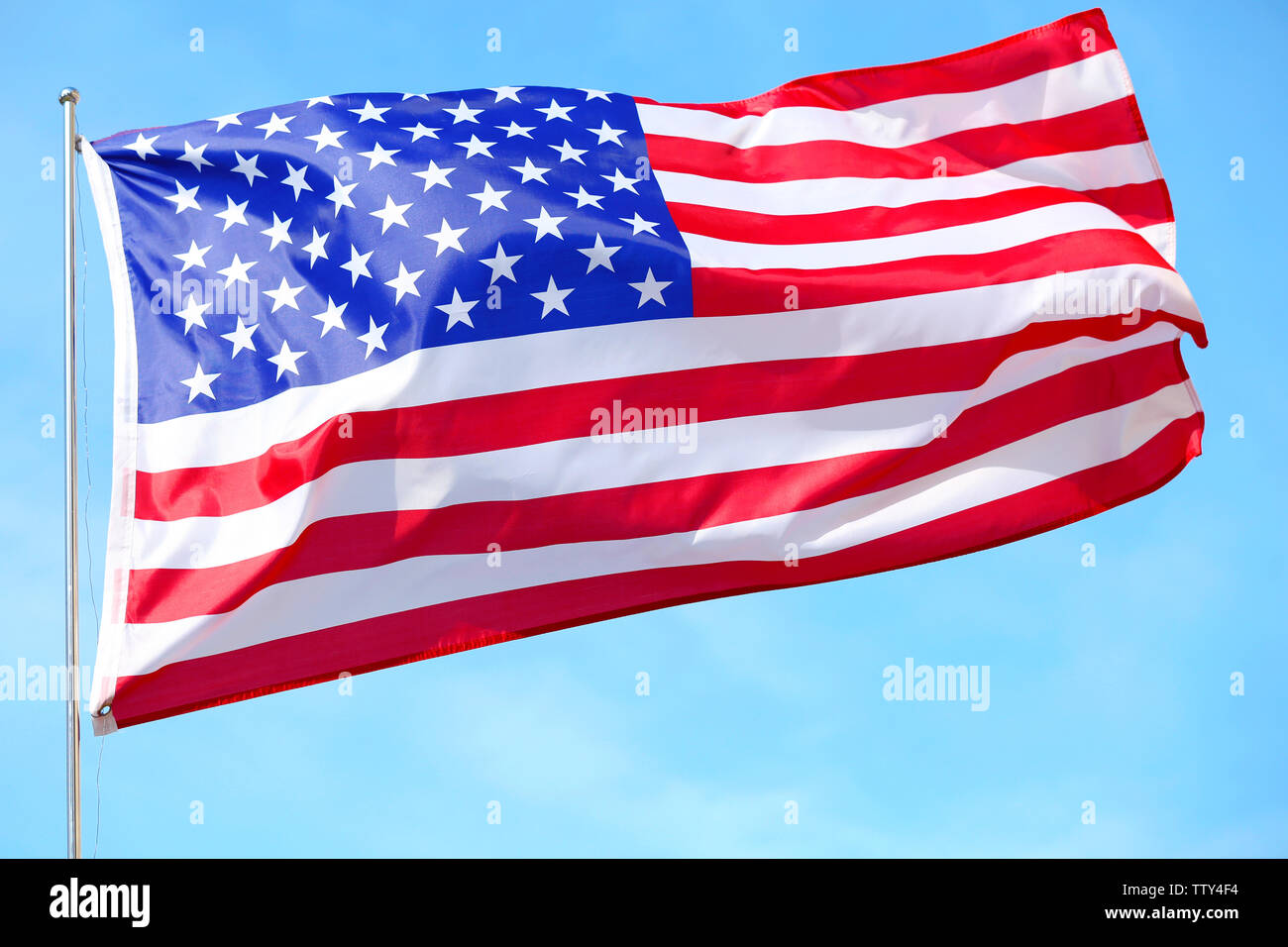 Ruffled American flag on blue sky background Stock Photo - Alamy