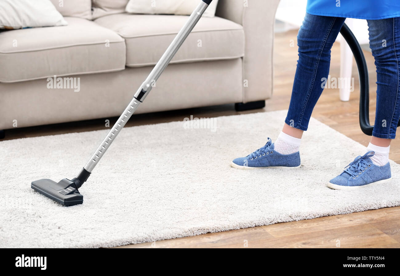 Cleaner hoovering carpet in room Stock Photo - Alamy