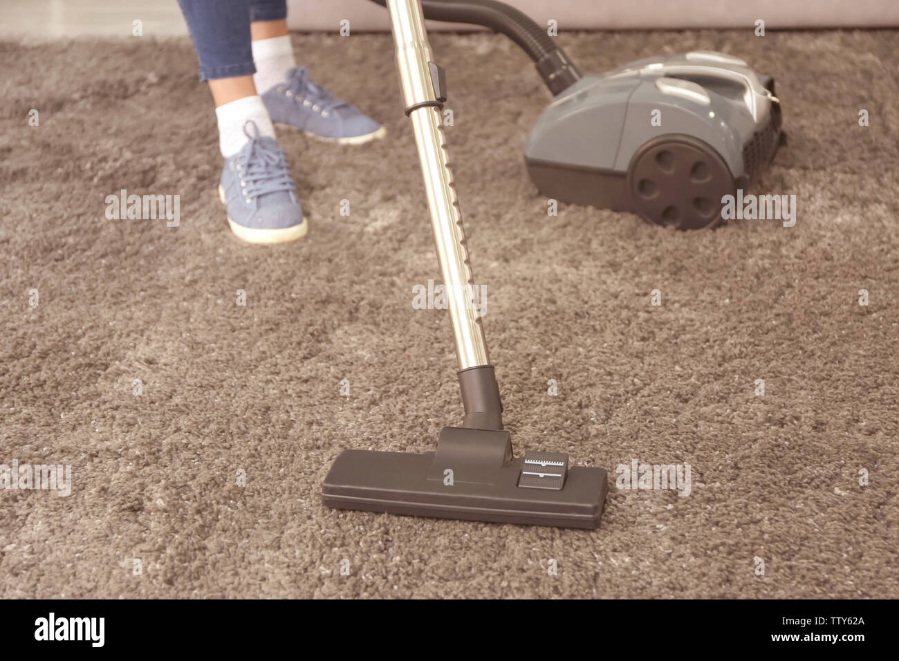 Cleaner hoovering carpet in room Stock Photo - Alamy