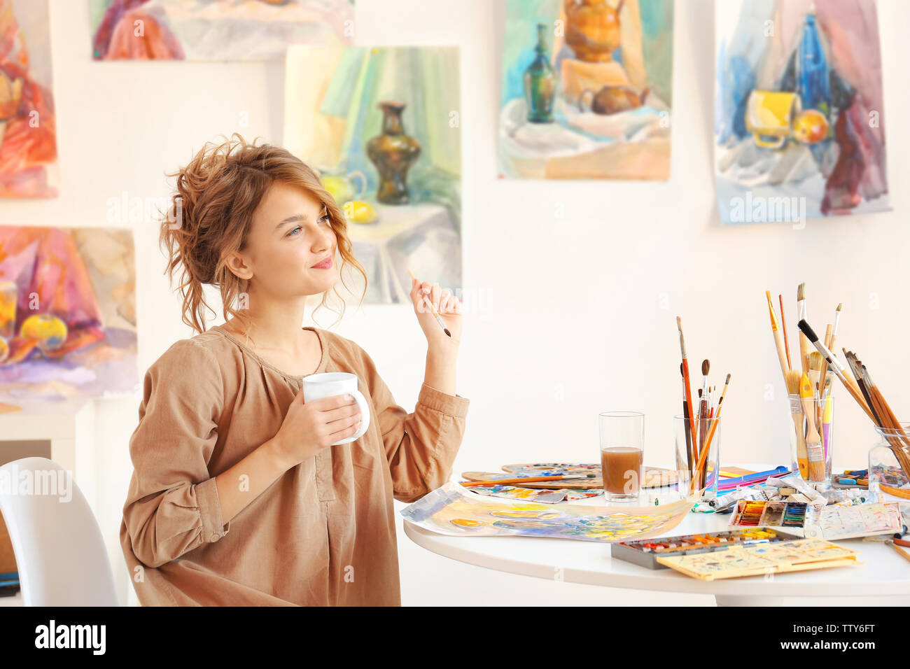 Young female artist drinking coffee in studio Stock Photo - Alamy