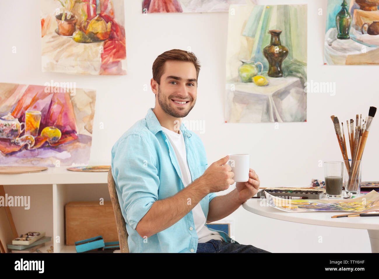 Young male artist drinking coffee in studio Stock Photo - Alamy