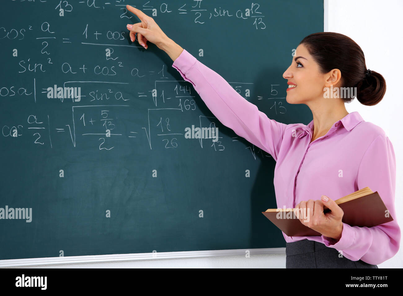 Young female teacher beside blackboard on white background Stock Photo ...