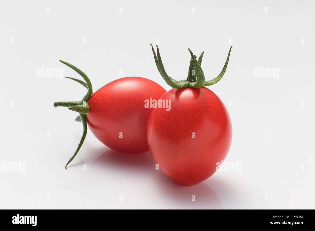 Fresh little tomatoes against white background Stock Photo - Alamy