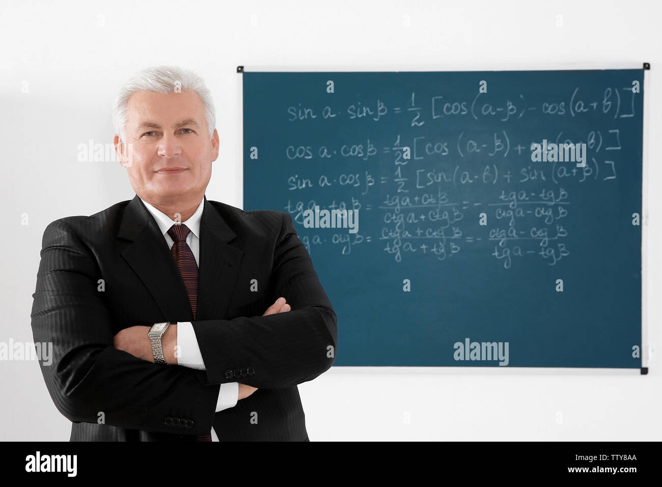 Senior teacher beside blackboard on white background Stock Photo - Alamy