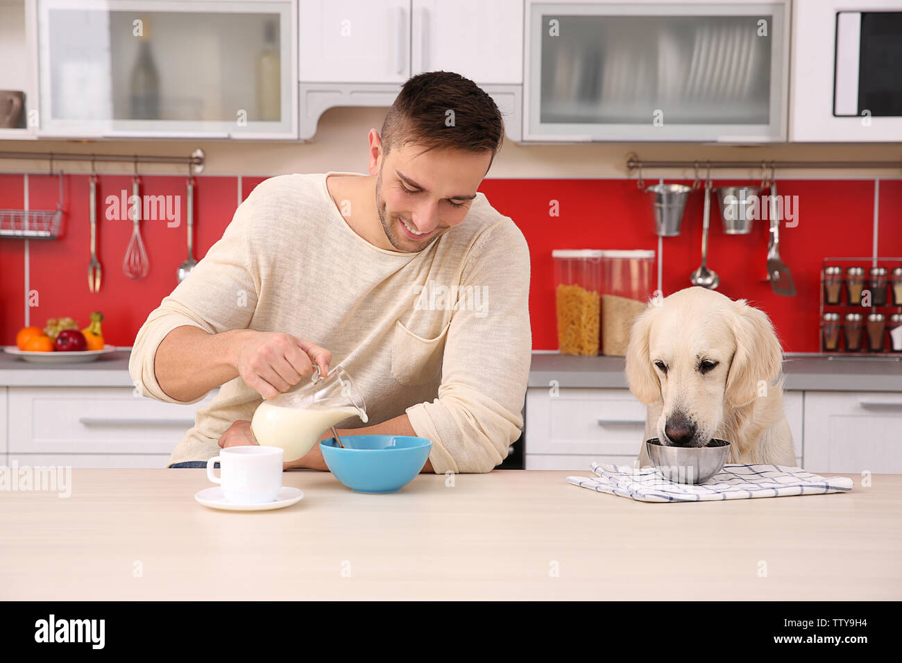 Man and dog enjoying breakfast at kitchen Stock Photo - Alamy