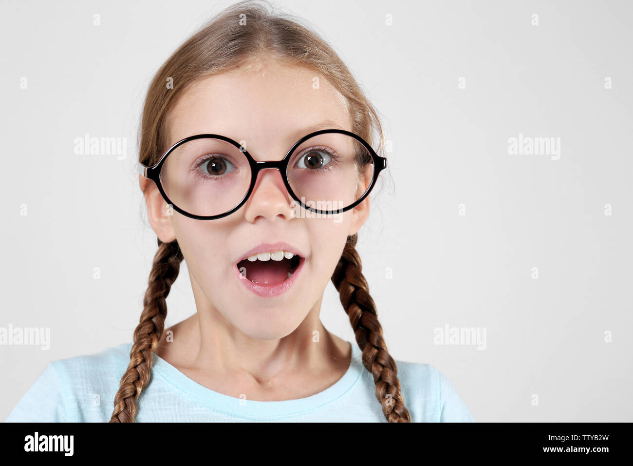 Little girl with spectacles on light background Stock Photo - Alamy