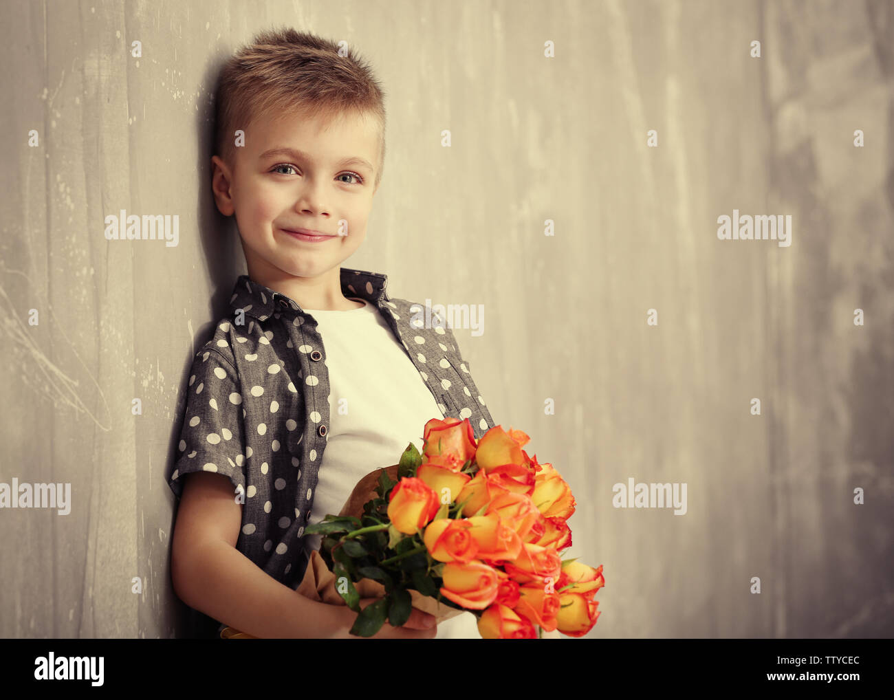 Cute boy with bouquet of beautiful flowers near grunge wall Stock Photo ...