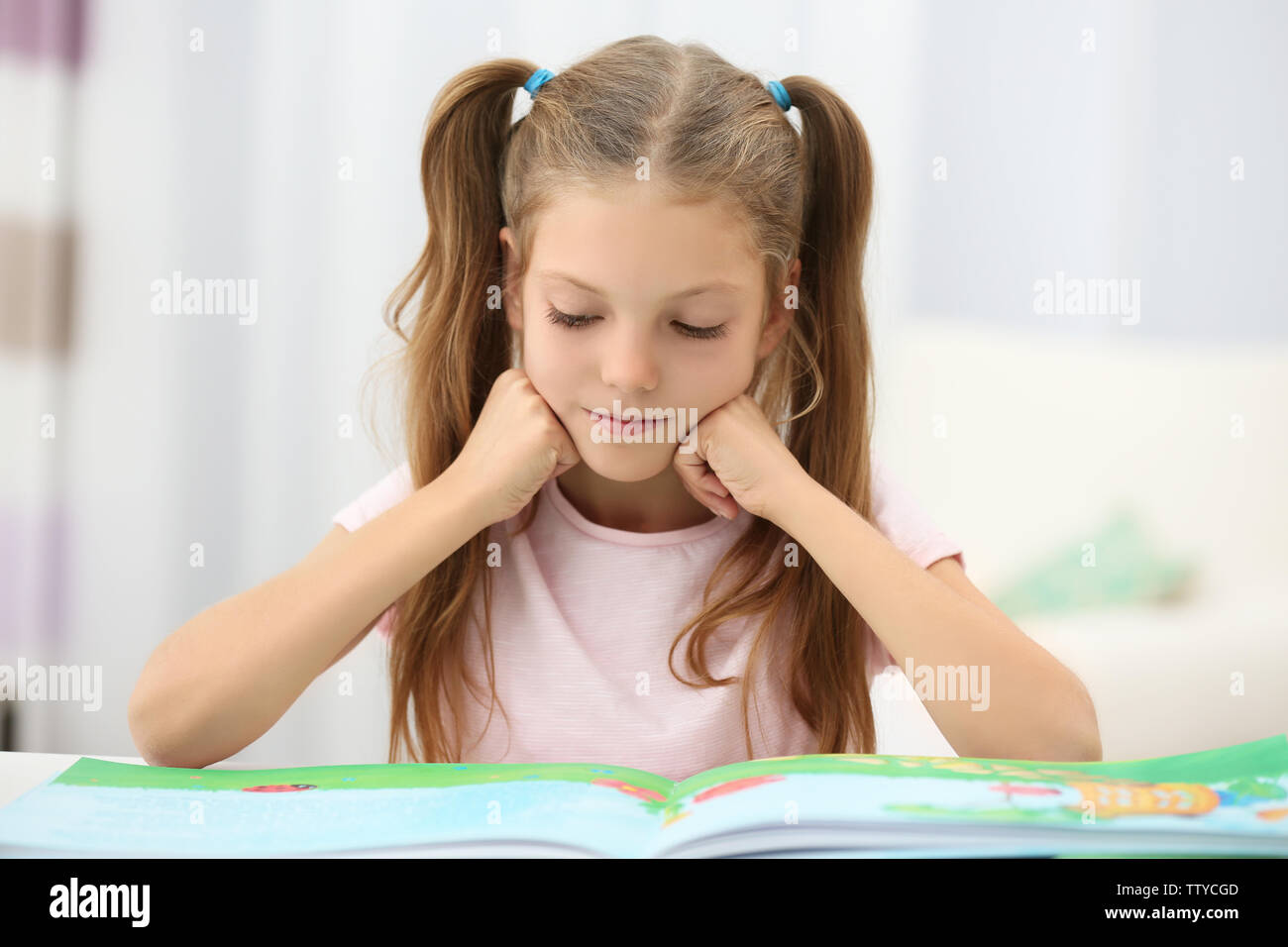 Cute girl reading book at home Stock Photo - Alamy