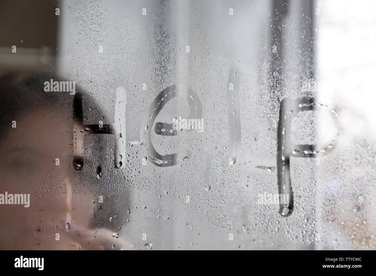Word HELP written by young woman on steamy window, view from outside ...