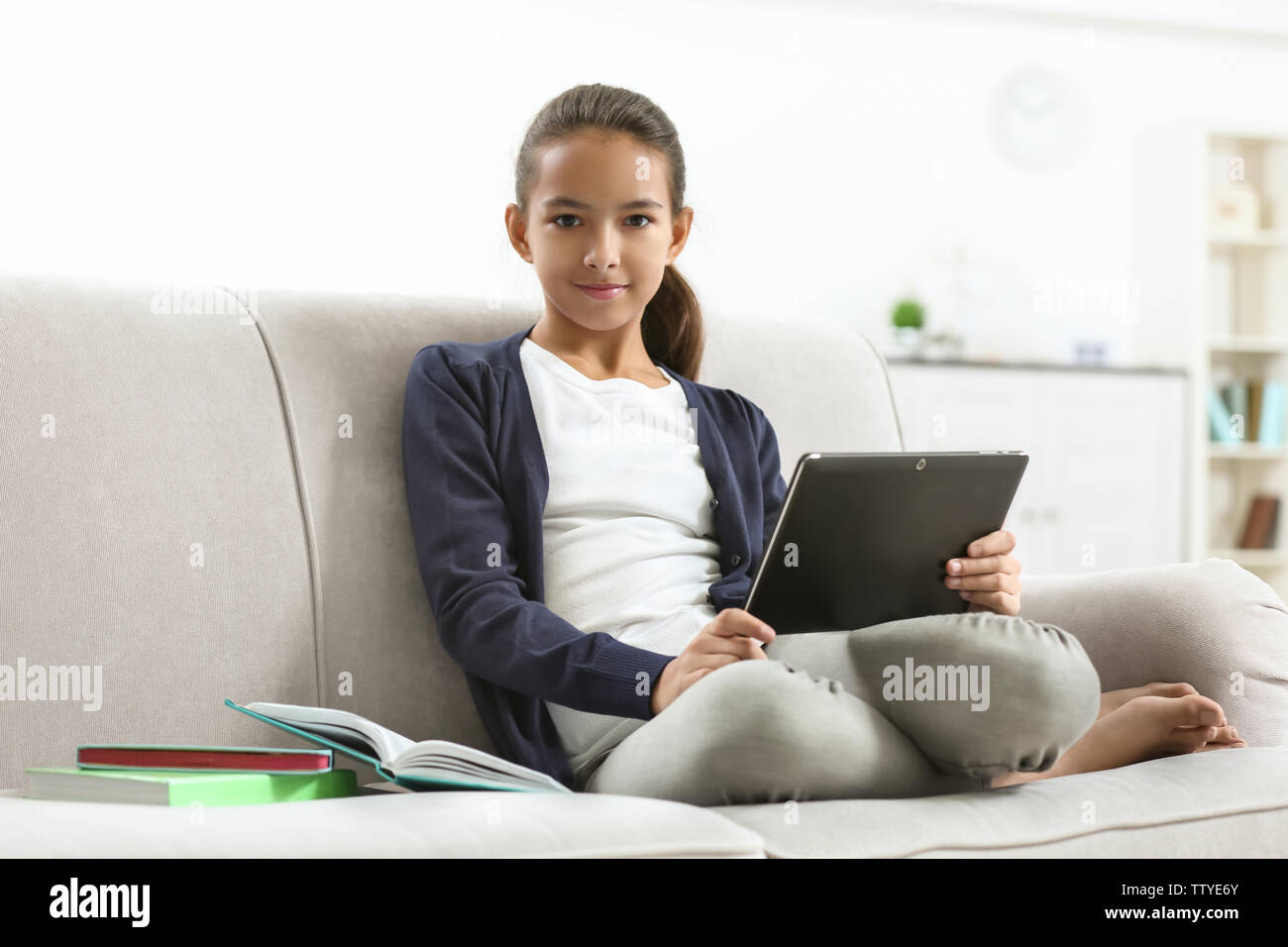 Cute girl sitting on sofa with tablet computer Stock Photo - Alamy