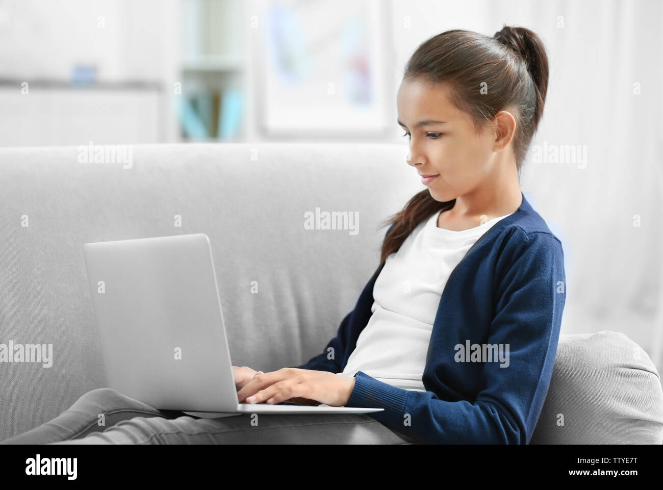 Cute girl sitting on sofa with laptop Stock Photo - Alamy