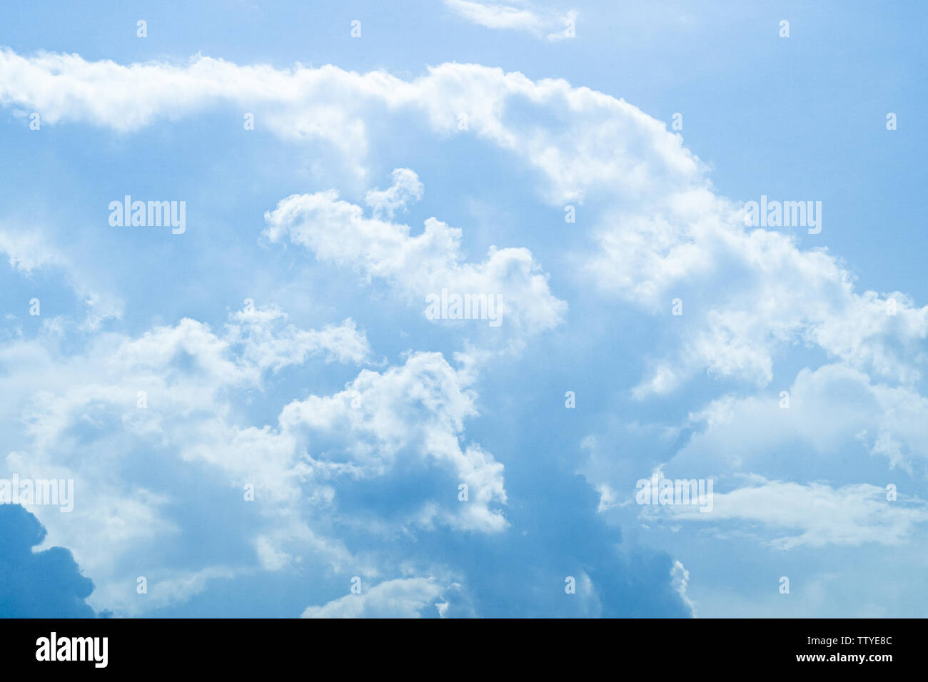 Sunny blue sky with soft clouds and bright sun against green trees ...