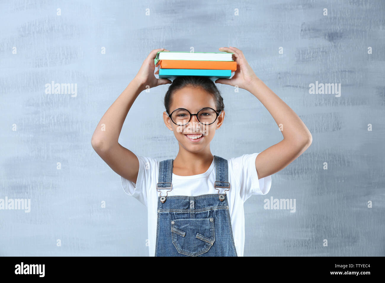 Cute girl with books on color background Stock Photo - Alamy