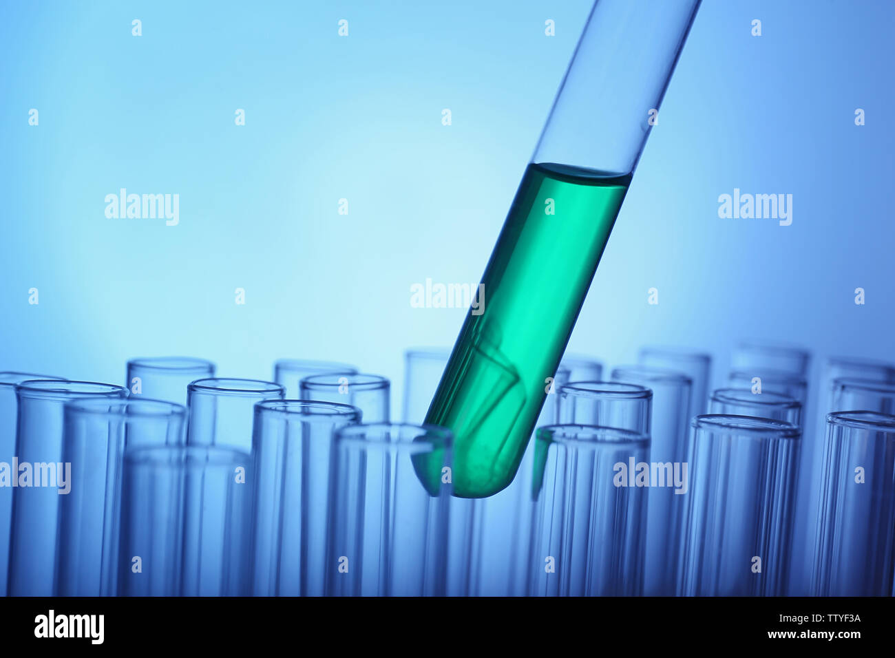 Test tube with green sample on light blue background Stock Photo - Alamy