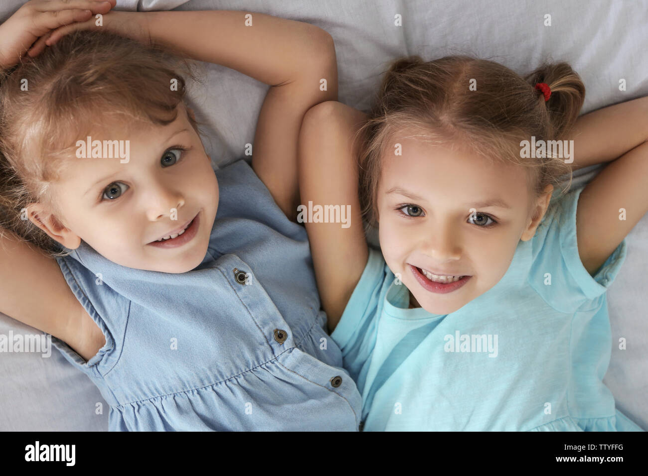 Adorable little sisters lying in bed, top view Stock Photo - Alamy