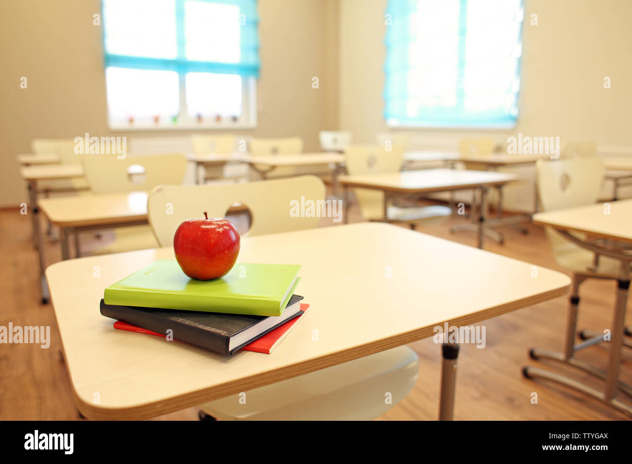 Stack of books and apple on desk at classroom Stock Photo - Alamy