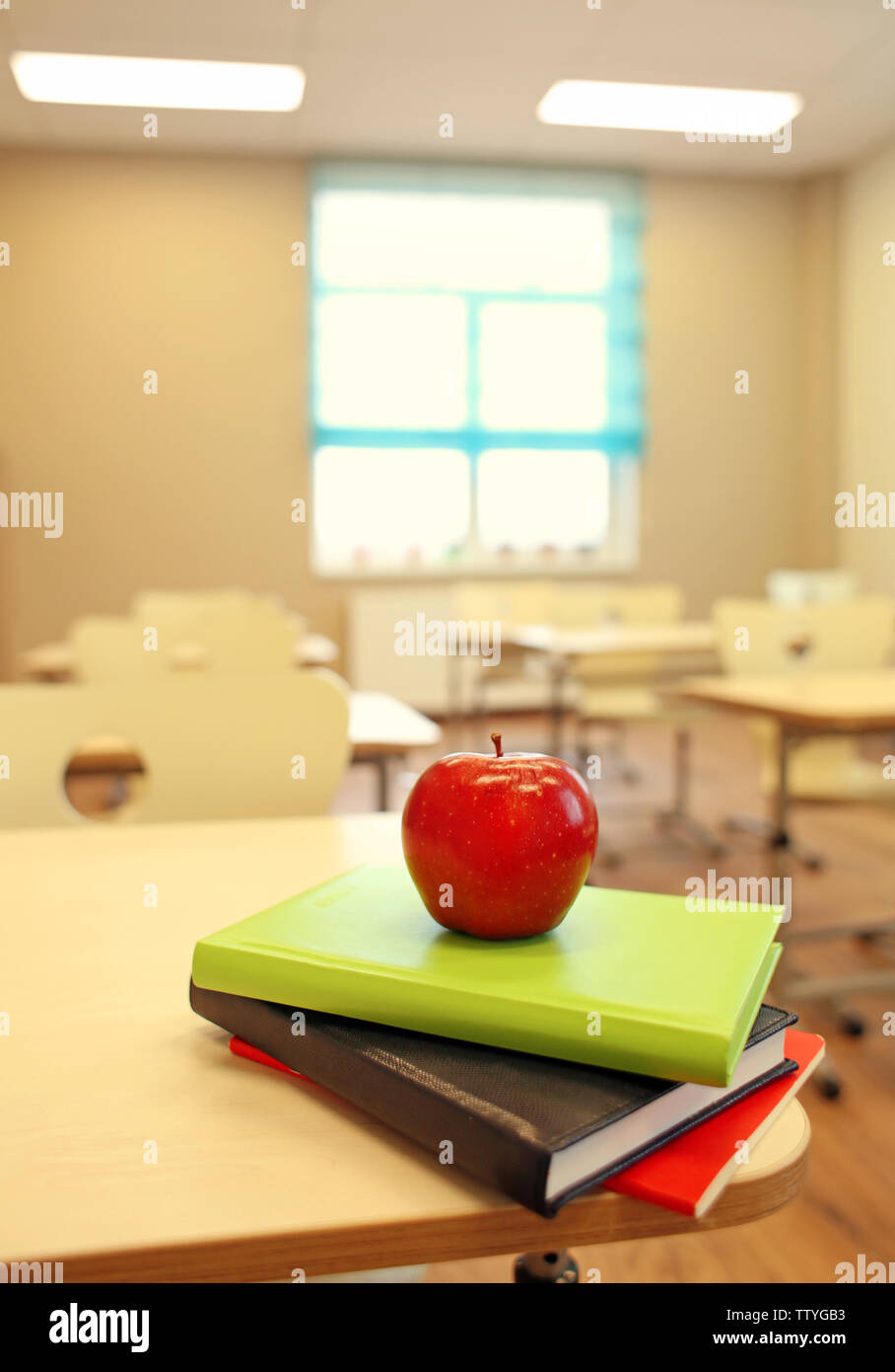 Stack of books and apple on desk at classroom Stock Photo - Alamy