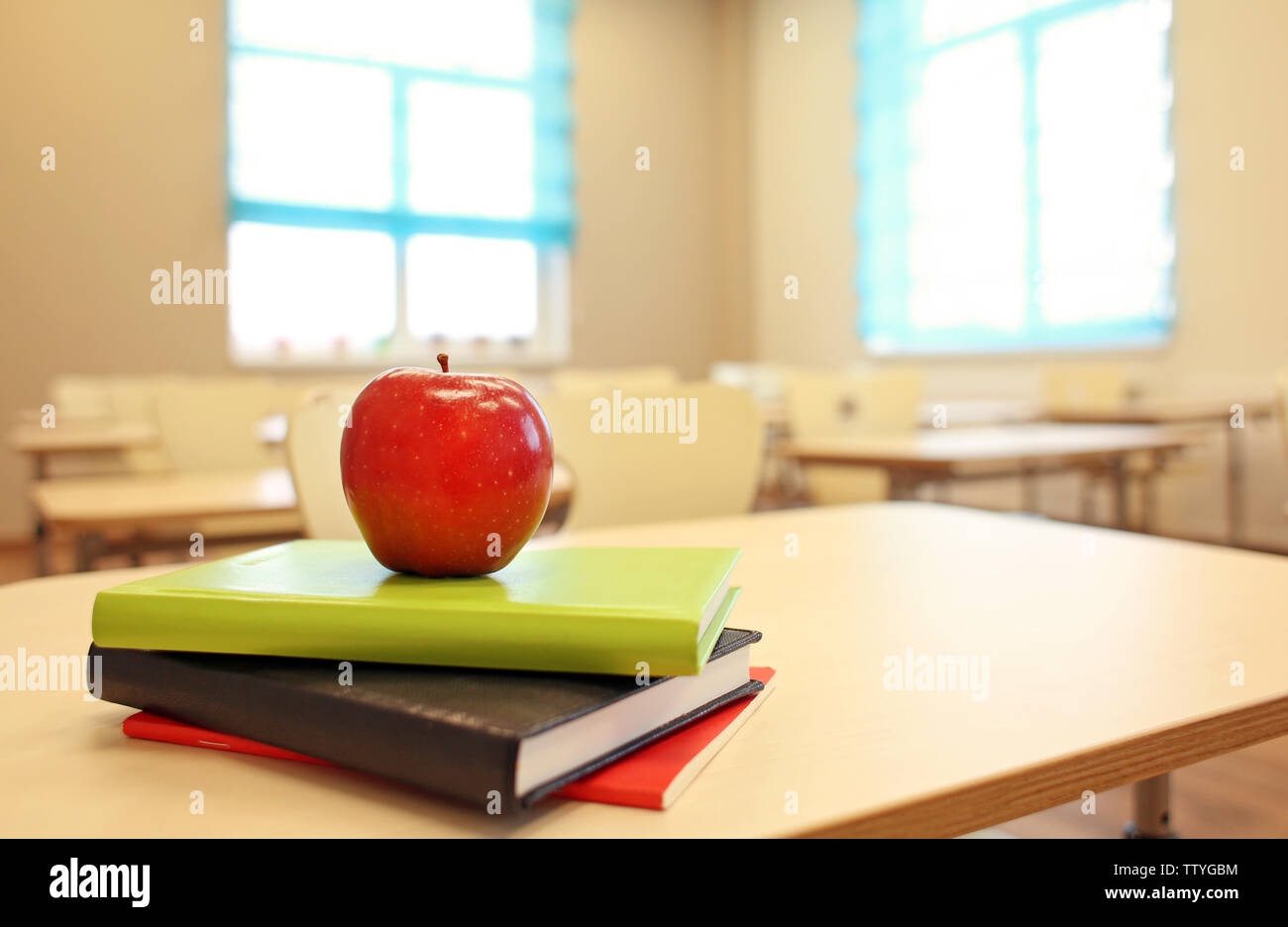 Stack of books and apple on desk at classroom Stock Photo - Alamy