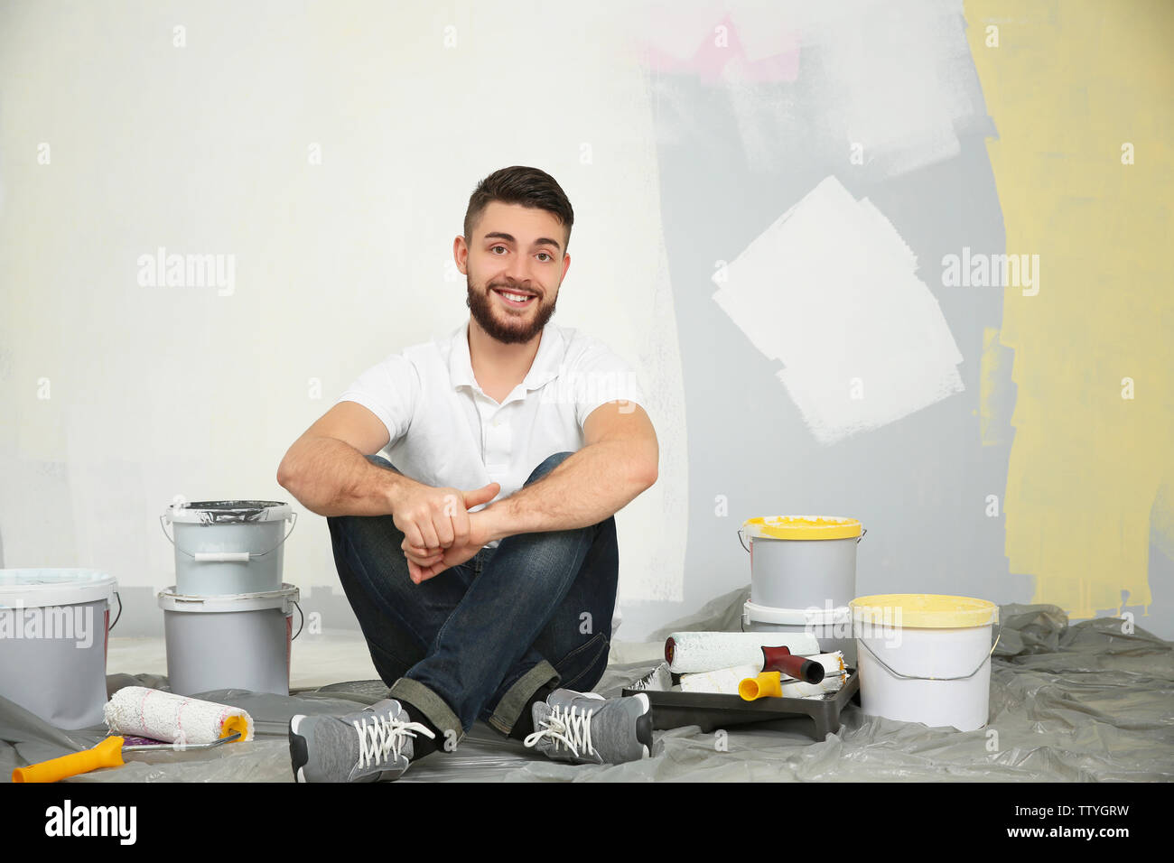 Young male worker with tools sitting on floor Stock Photo - Alamy