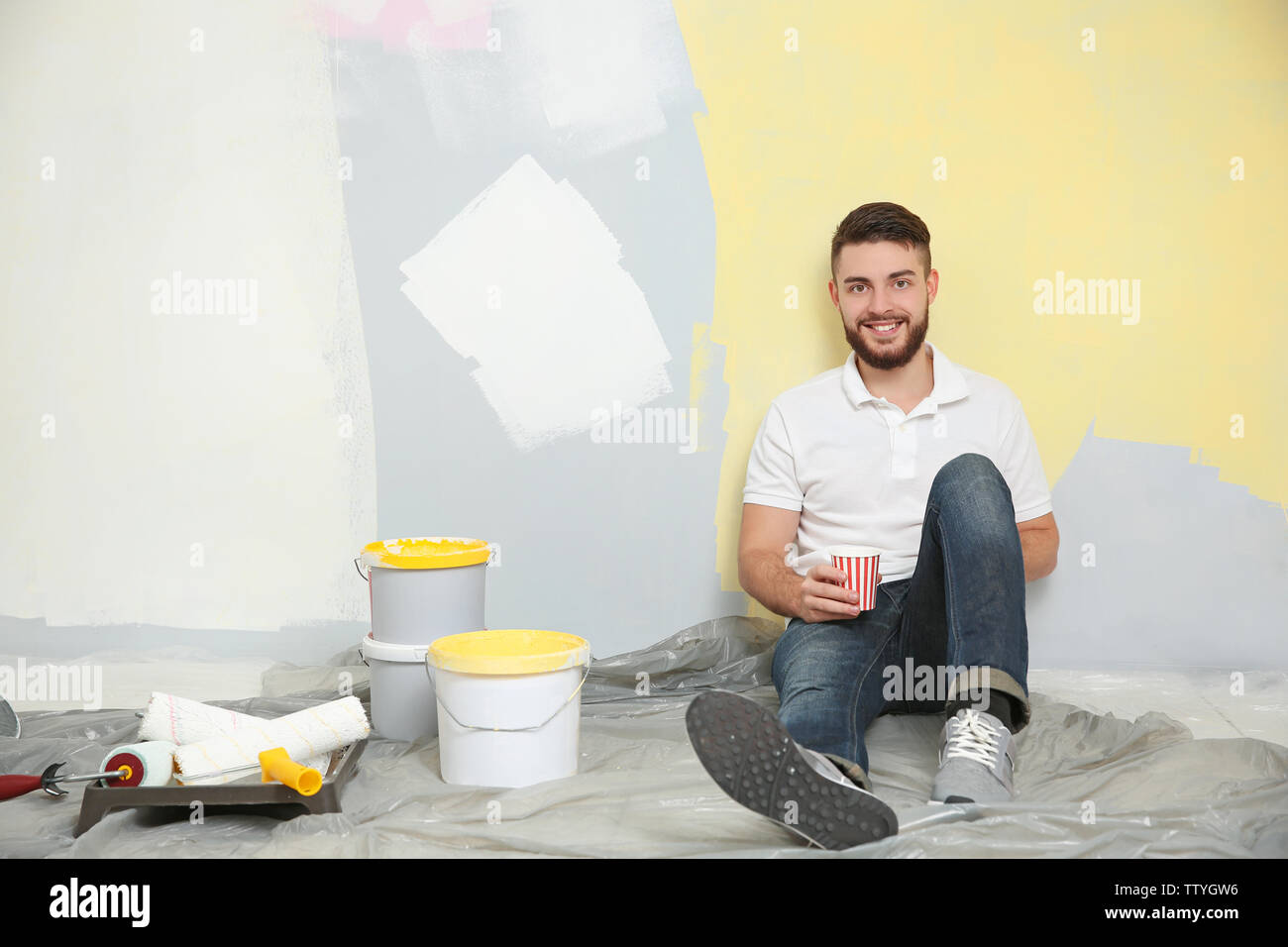 Young male worker with tools sitting on floor Stock Photo - Alamy