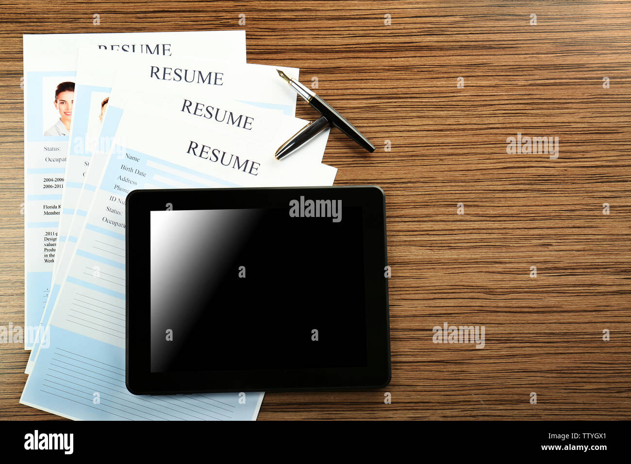 Employer workplace with tablet and resumes Stock Photo - Alamy