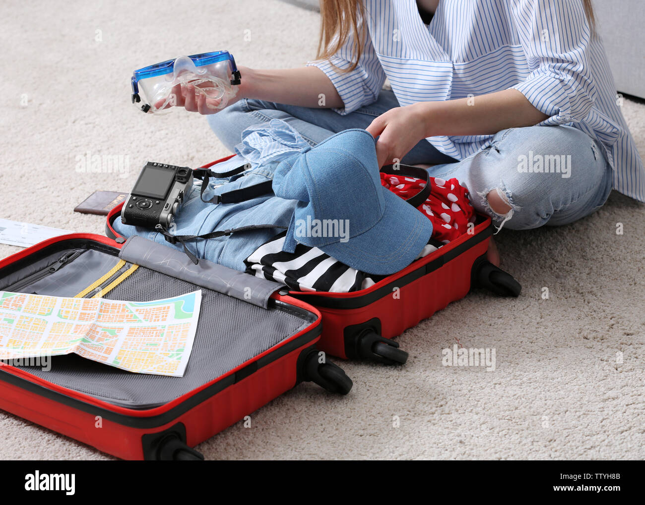 Woman packing her red suitcase in living room Stock Photo - Alamy