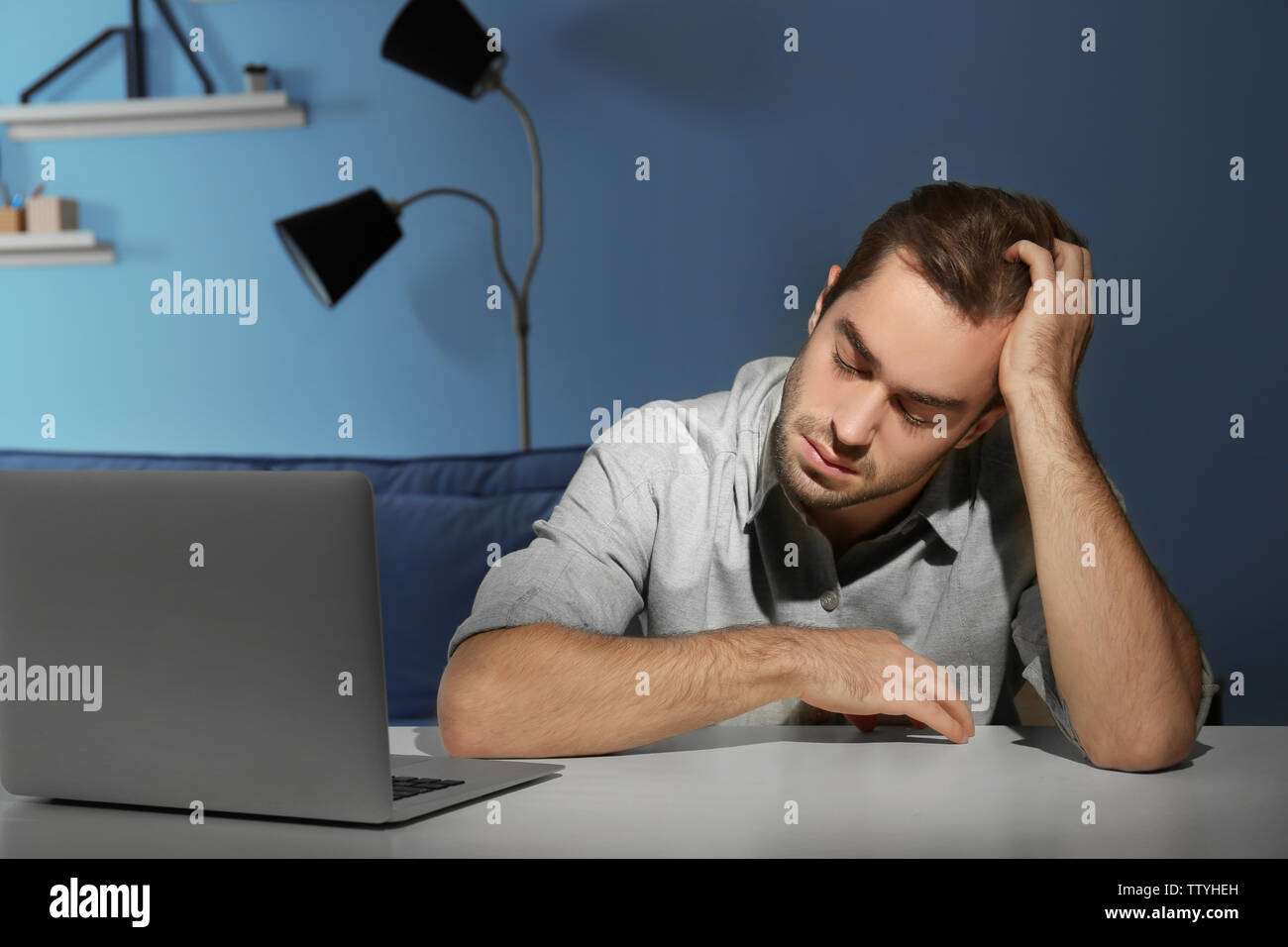 Tired young man working with laptop at home in evening Stock Photo - Alamy