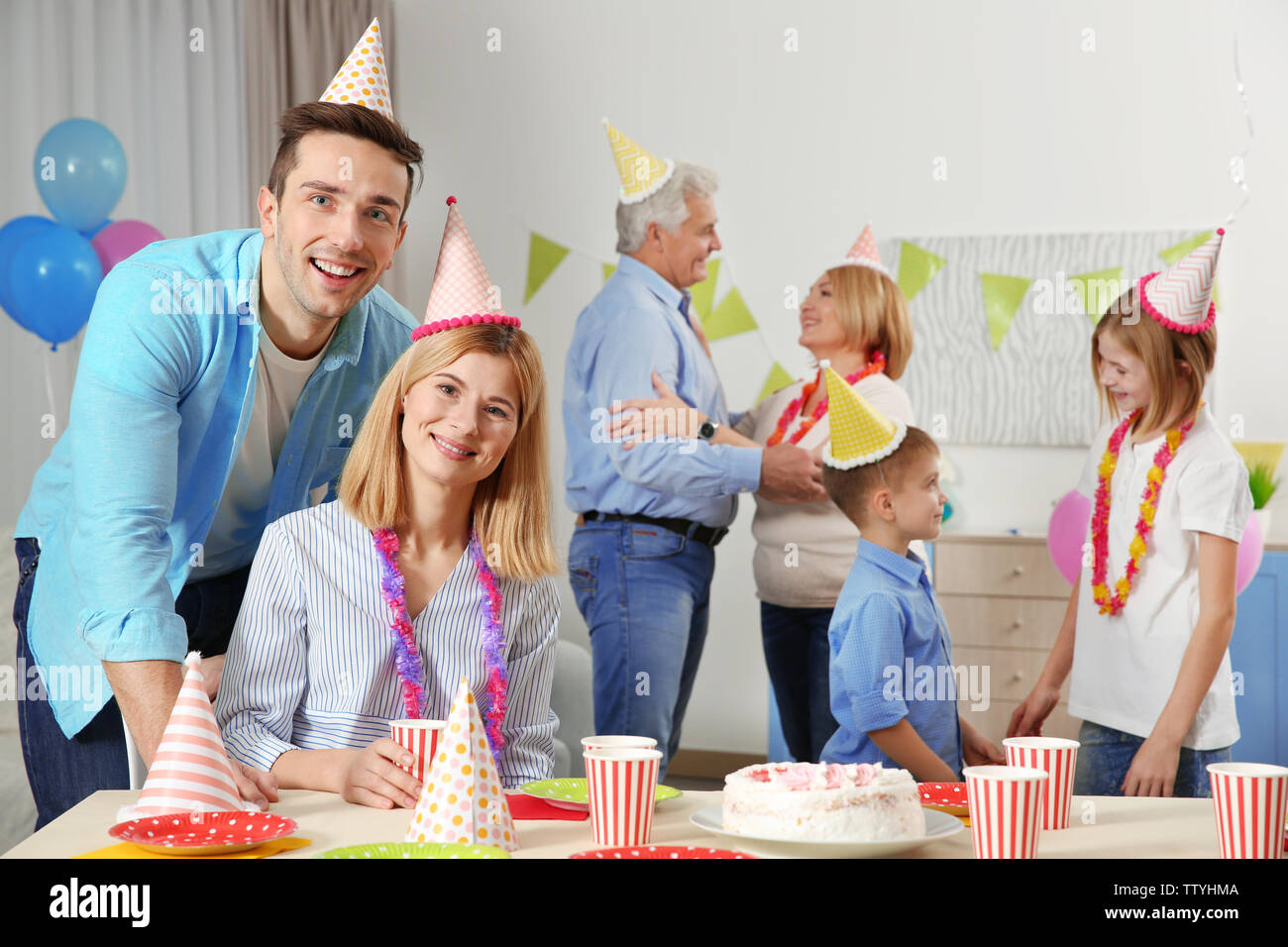 Birthday party. Happy parents sitting at table Stock Photo - Alamy