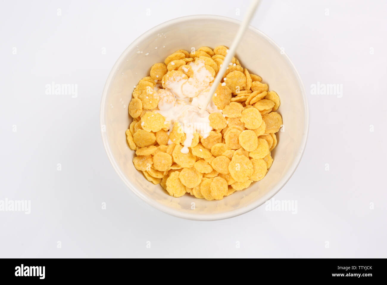 Pouring milk into bowl with corn cereals on white background Stock ...