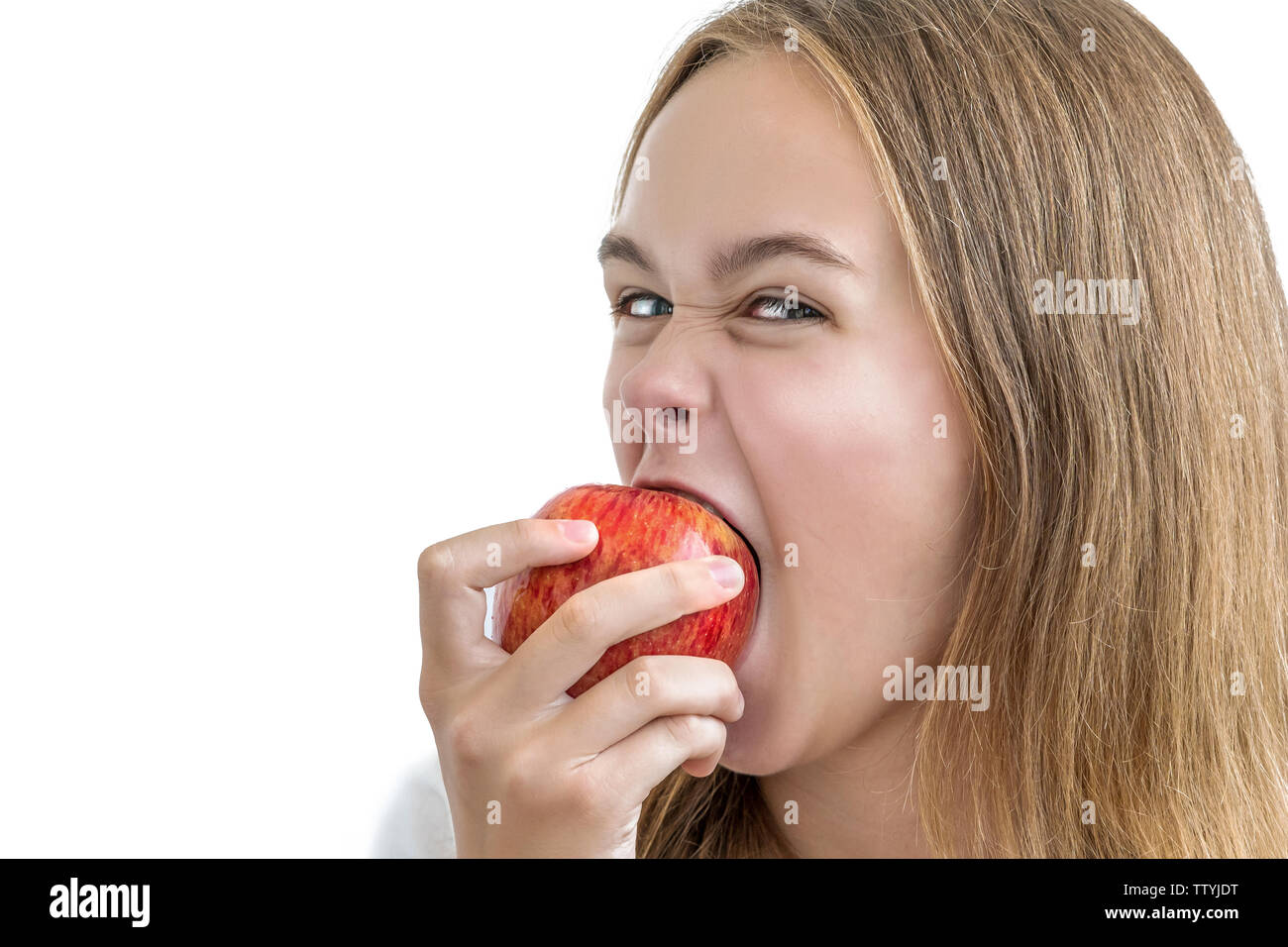 Funny angry woman eats an apple and looks into the camera on white ...