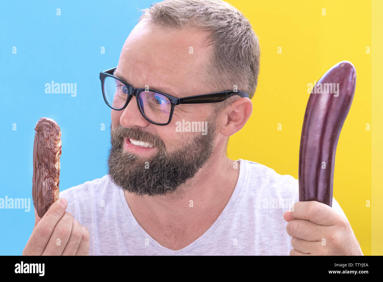 Funny beard man thinking what to eat between an eggplant and a eclair ...