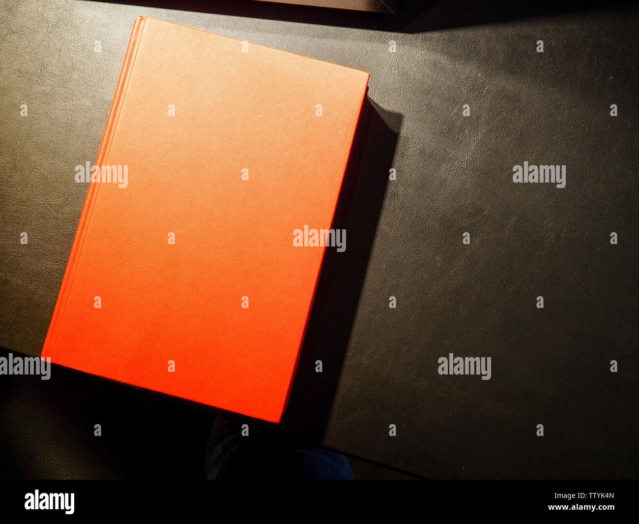 Red hardback book on black table, Office dark table. Mock up book blank ...